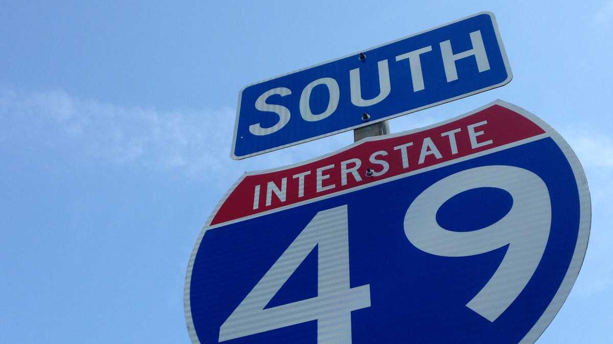 Crews place Interstate 49 signs along roadway during rush-hour commute