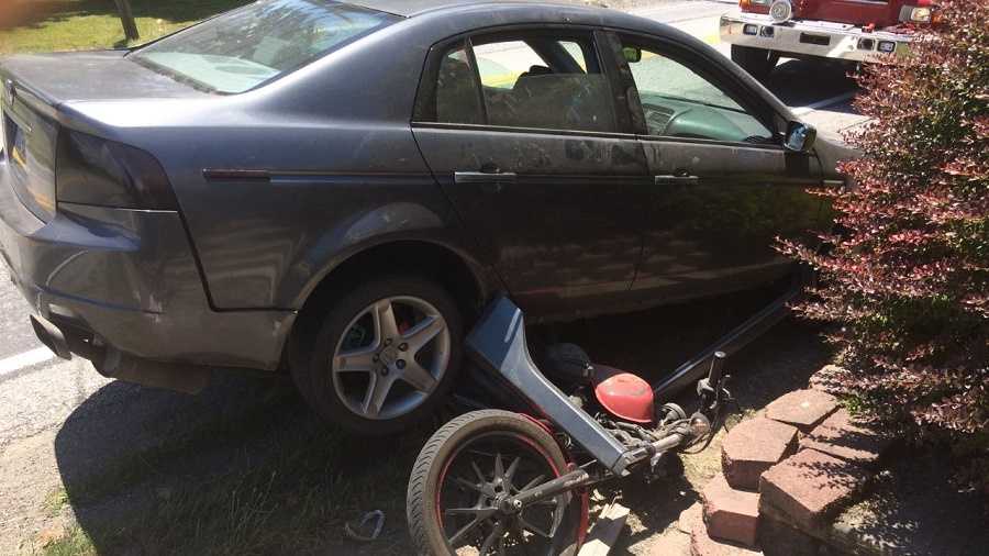 Motorcyclist pinned under car following crash