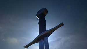 Man wielding medieval-type sword over head shot by officer