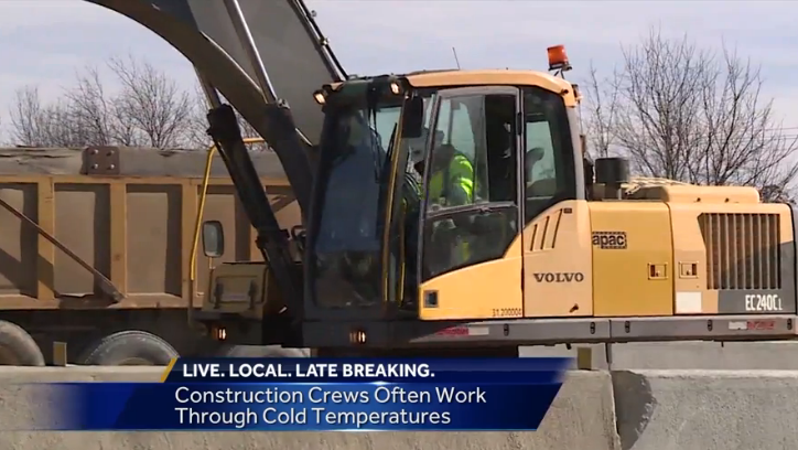 Construction workers try to keep warm as freezing weather moves in