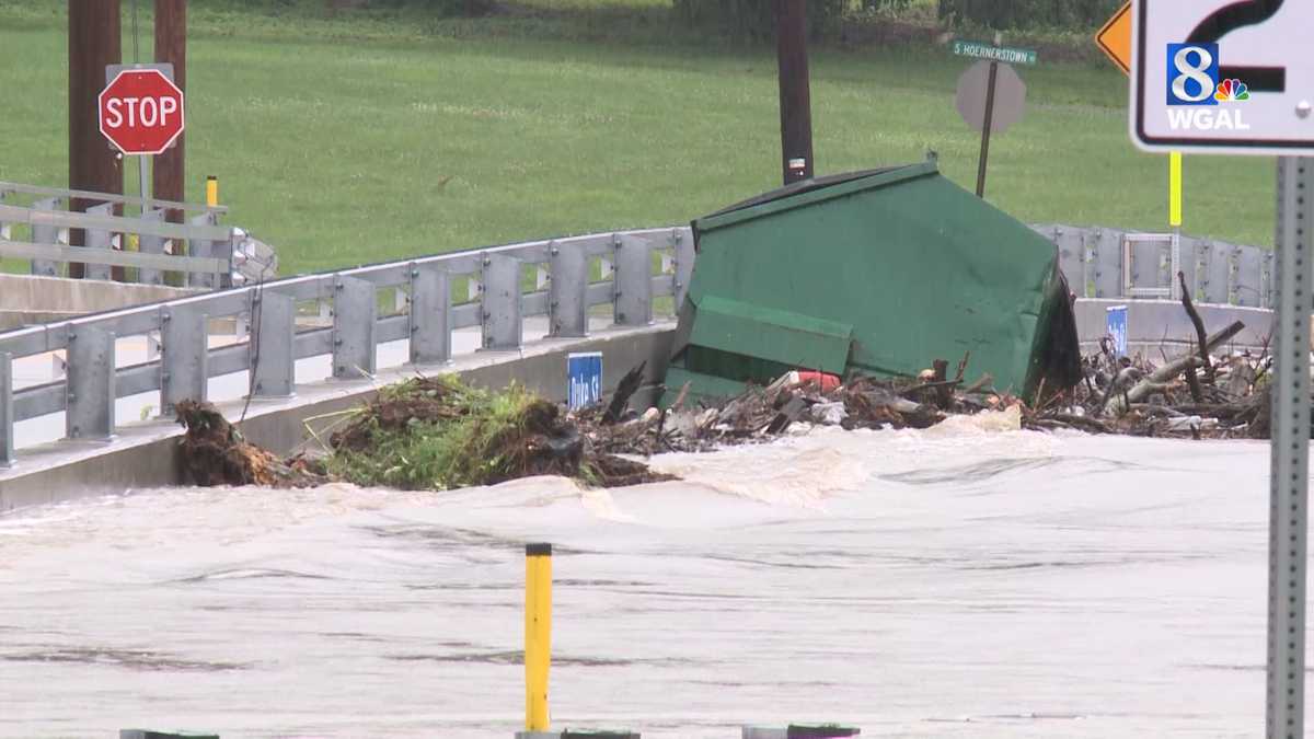 Debris,including Dumpster, piles against flooded bridge