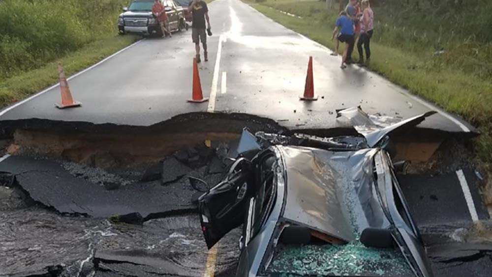 Road collapses under car that drove through barriers, emergency ...