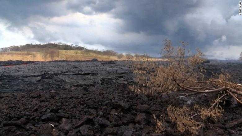 Farmers work next to lava flow