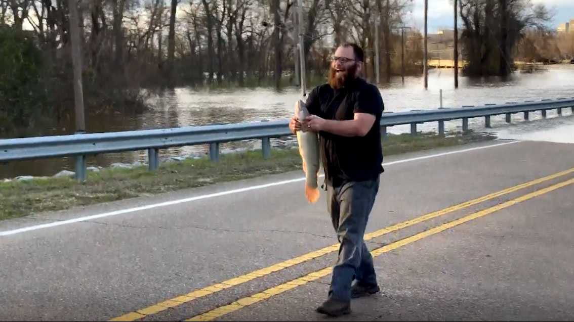 Man catches fish in floodwaters