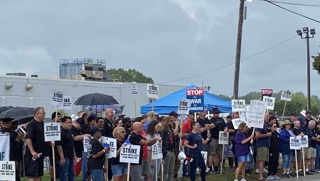 Union members stand in rain picketing outside Amcor in Des Moines