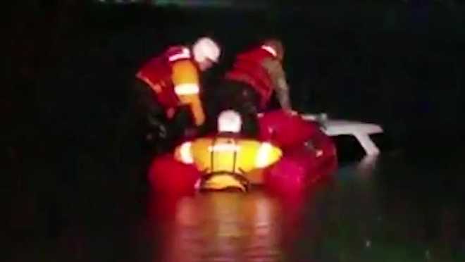 Police officer rescued from car stuck in rising floodwaters in ...