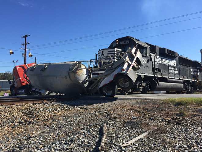 Tractor-trailer overturns after being hit by train, fire official says