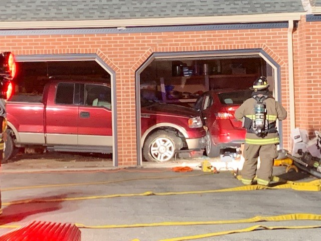 Pickup truck slams through side of garage, pushing car into house