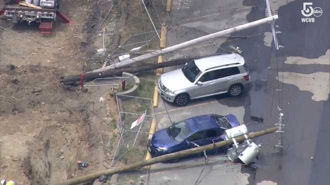 Utility poles come crashing down onto two parked vehicles