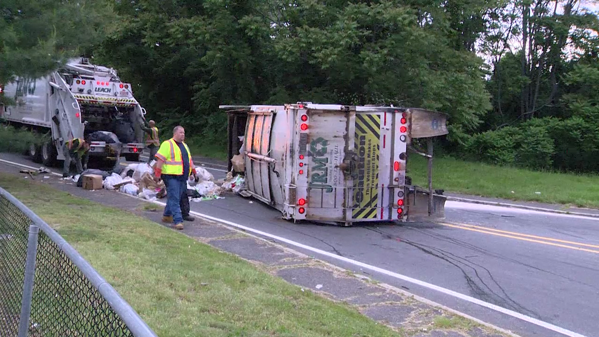 Trash truck rolls over, spills debris all over road