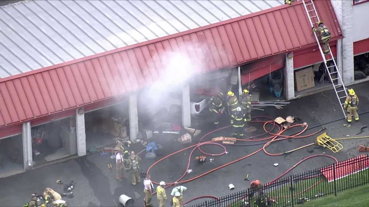 Pickup truck crashes into storage facility, catches fire