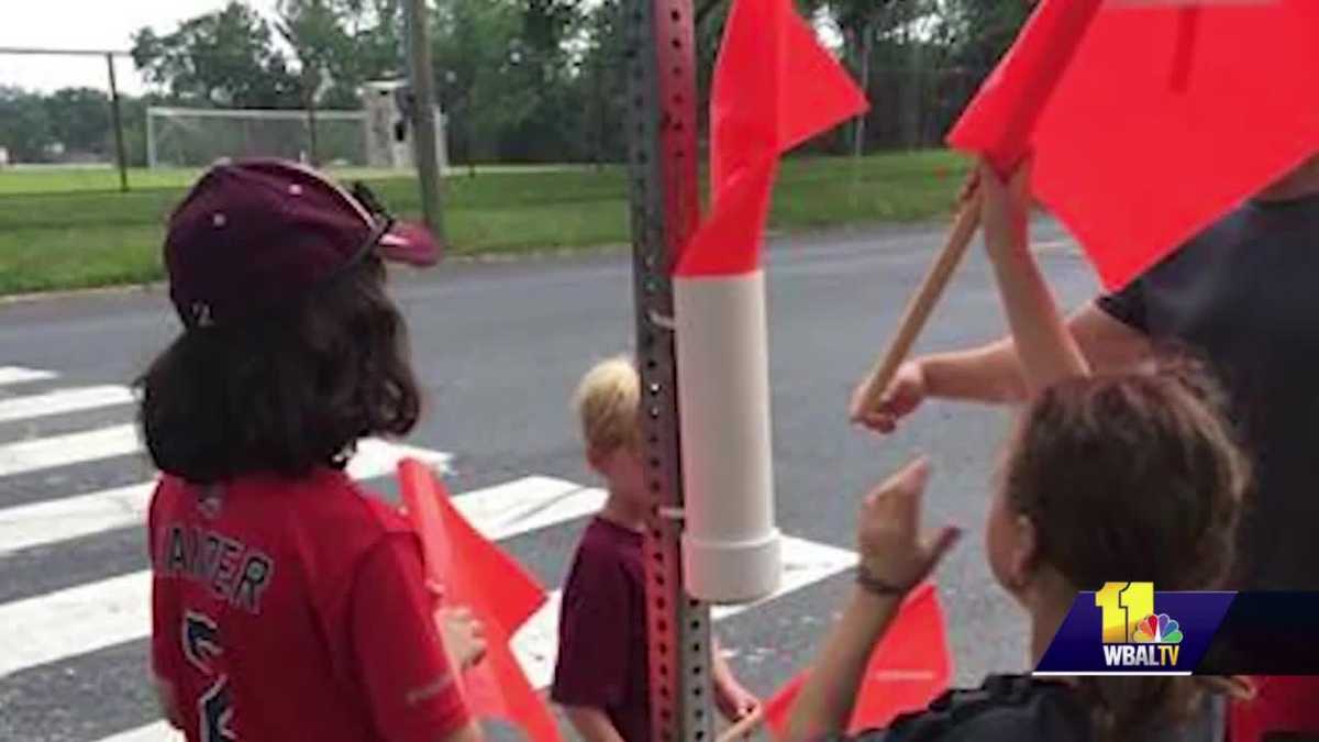 Parents buy orange flags to help children safely cross street